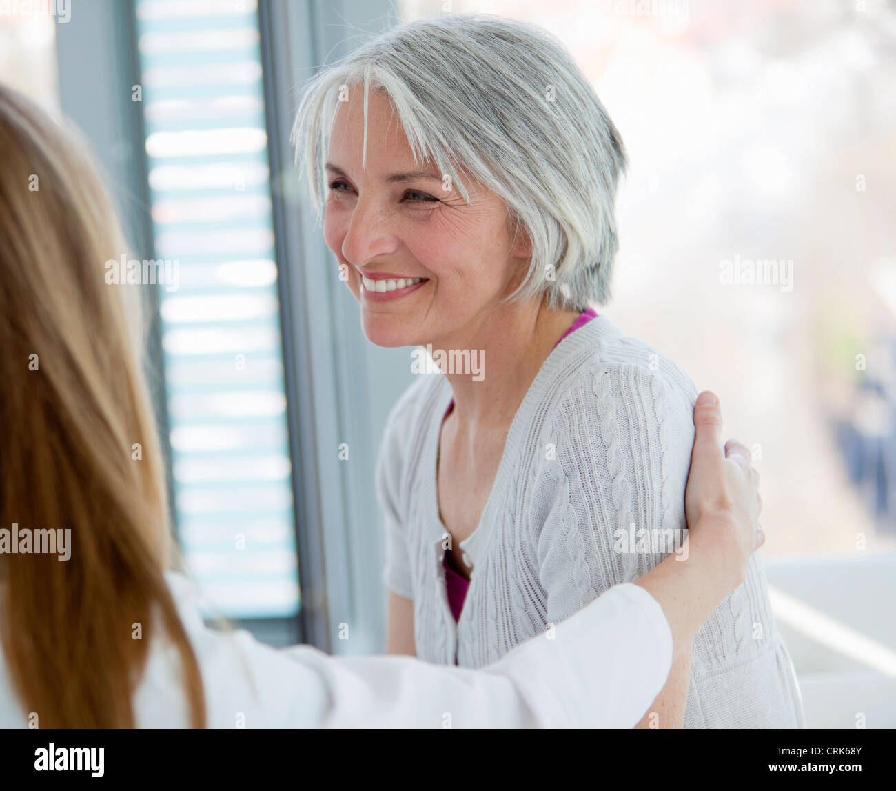 Doctor hugging smiling woman in office Stock Photo - Alamy
