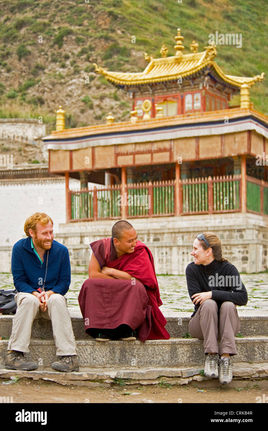 Western tourists interacting with a Tibetan Buddhist monk of the ...