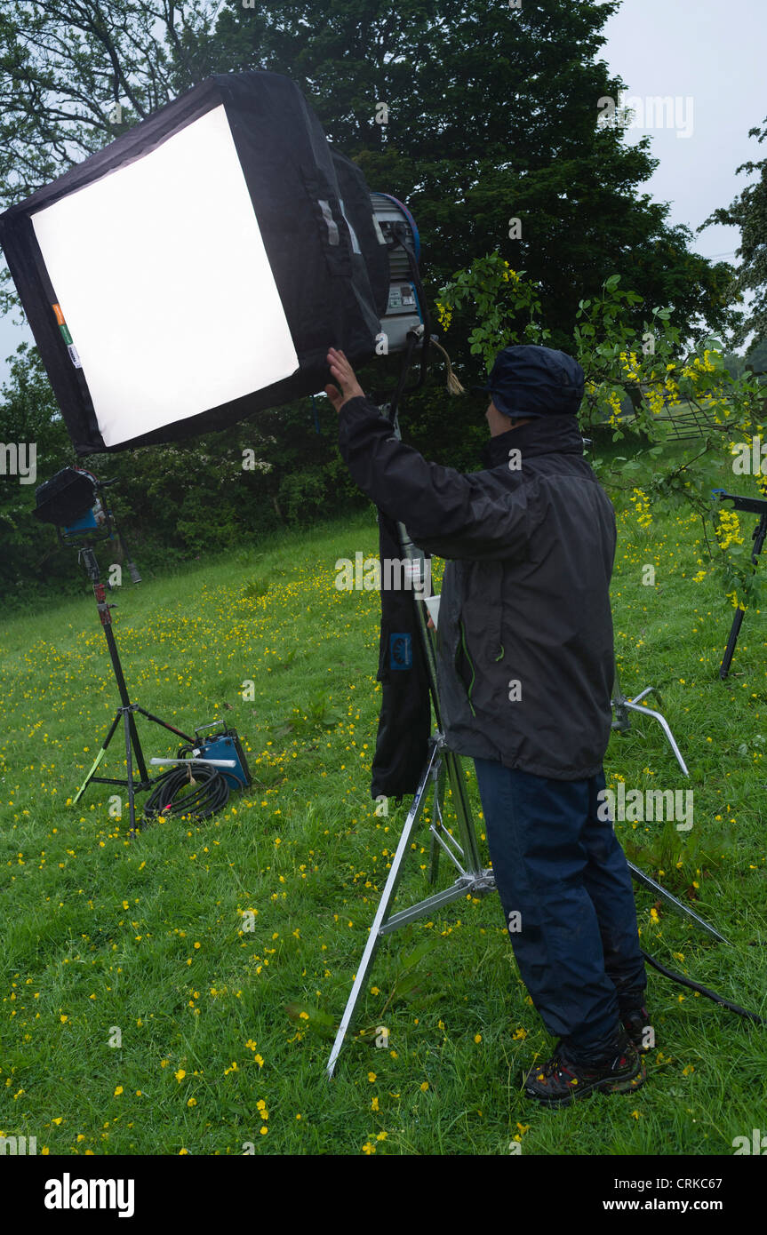 a man adjusting lighting equipment at a recording a television drama ...