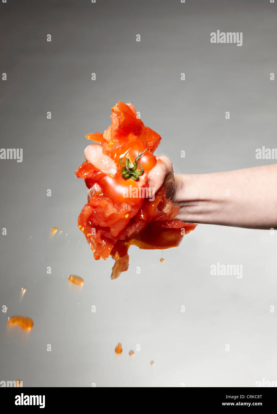 Hand squeezing raw tomato Stock Photo - Alamy