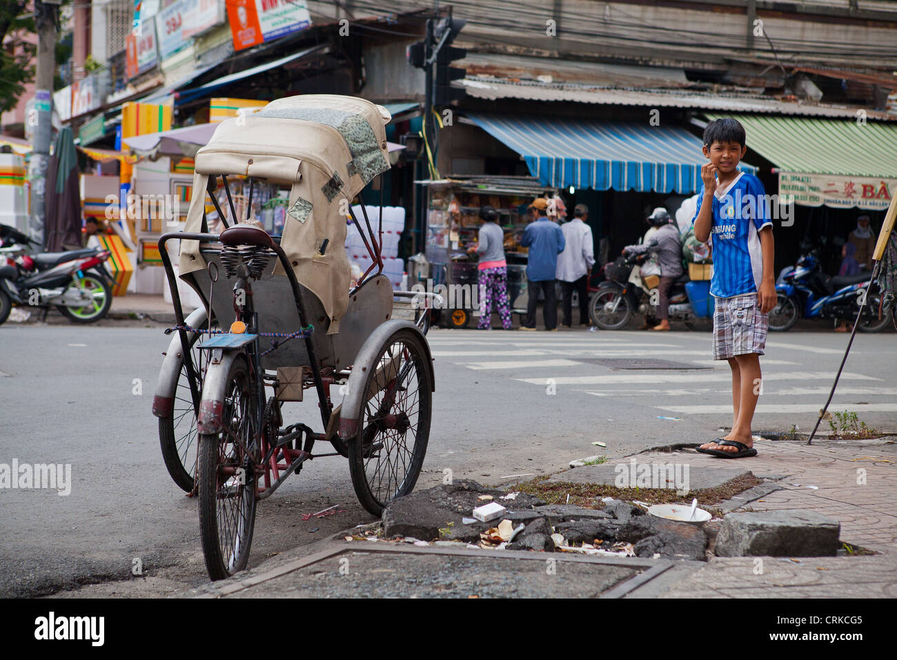 A young boy next to a cyclo in the streets of Ho Chi Minh City, Vietnam ...