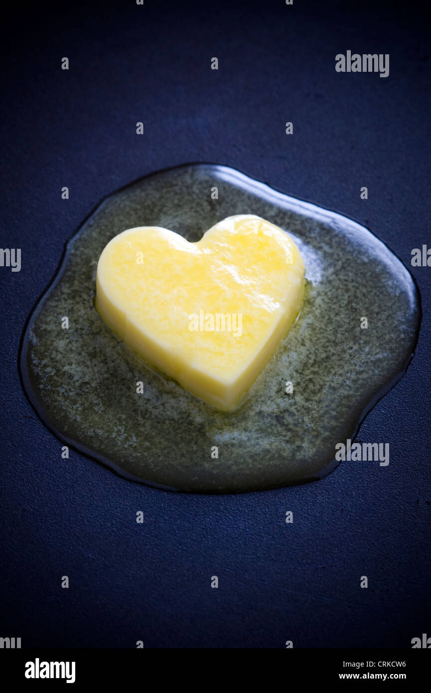 a heart shaped butter pat melting on a non-stick surface representing a ...