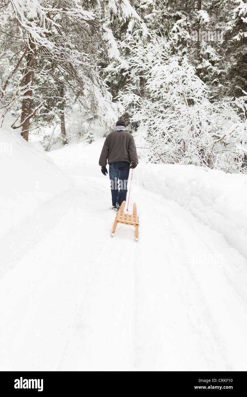 Man pulling sled in snowy field Stock Photo - Alamy