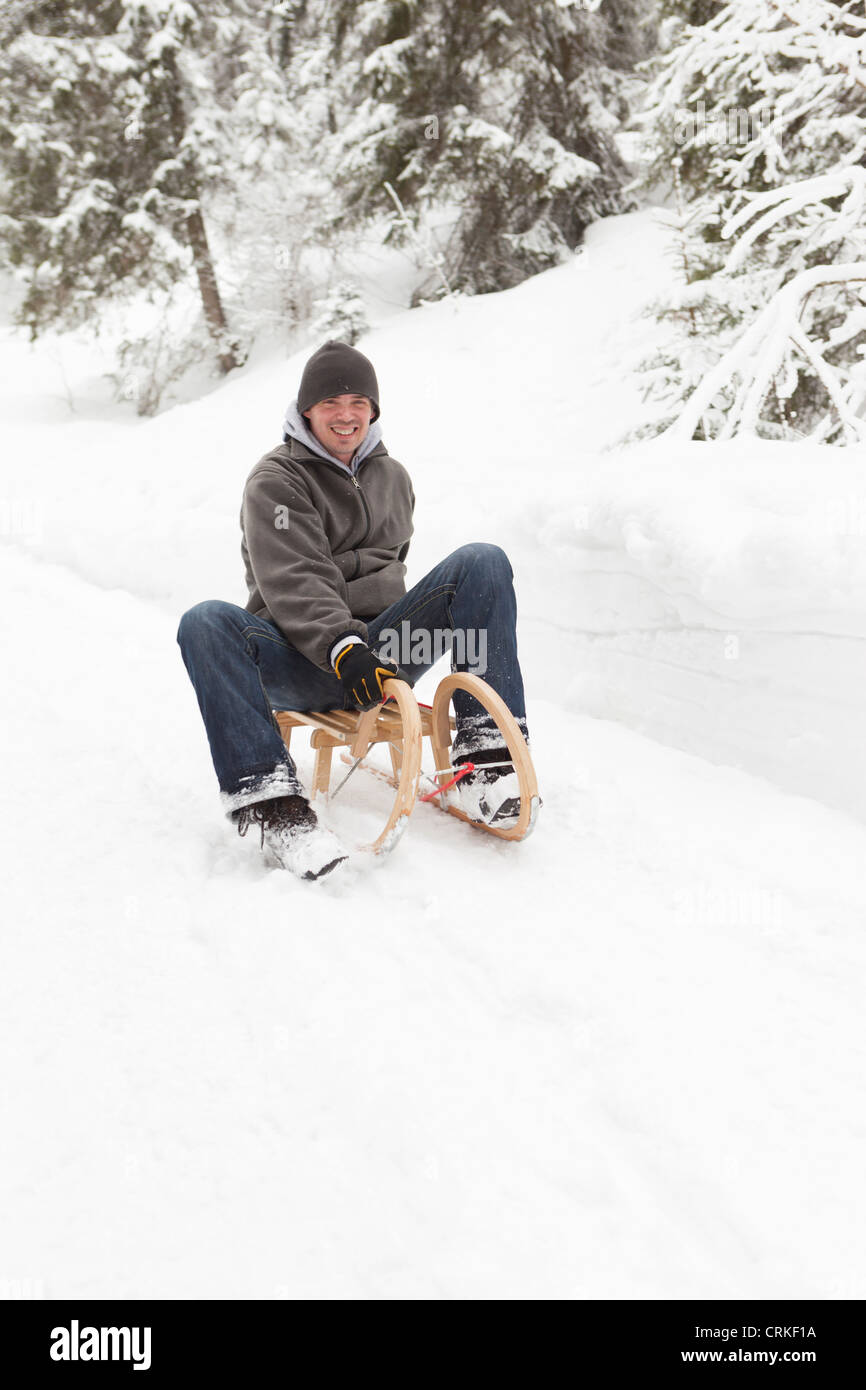 Man sitting on sled in snowy field Stock Photo - Alamy