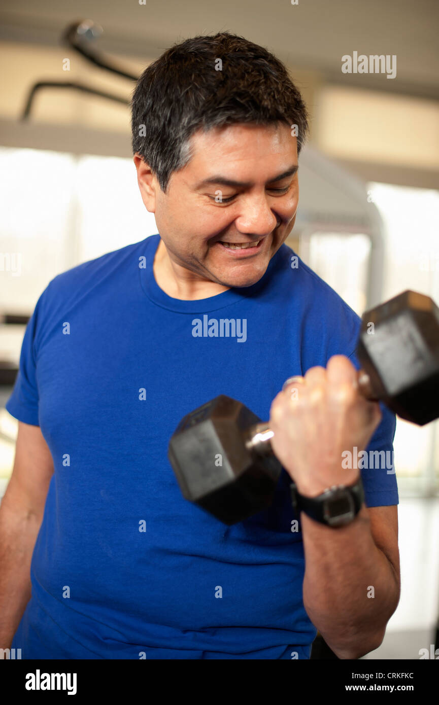 Smiling man lifting weights in gym Stock Photo - Alamy