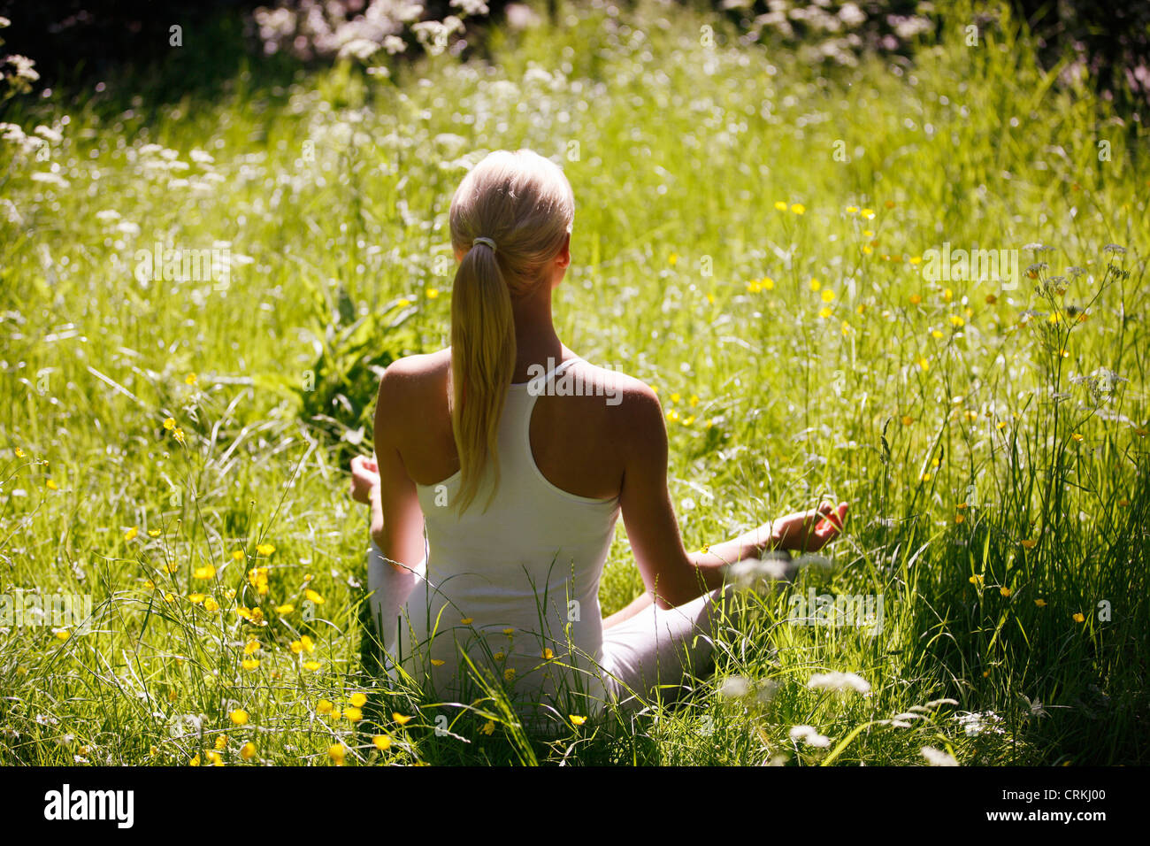 A young woman meditating outside, back view Stock Photo - Alamy