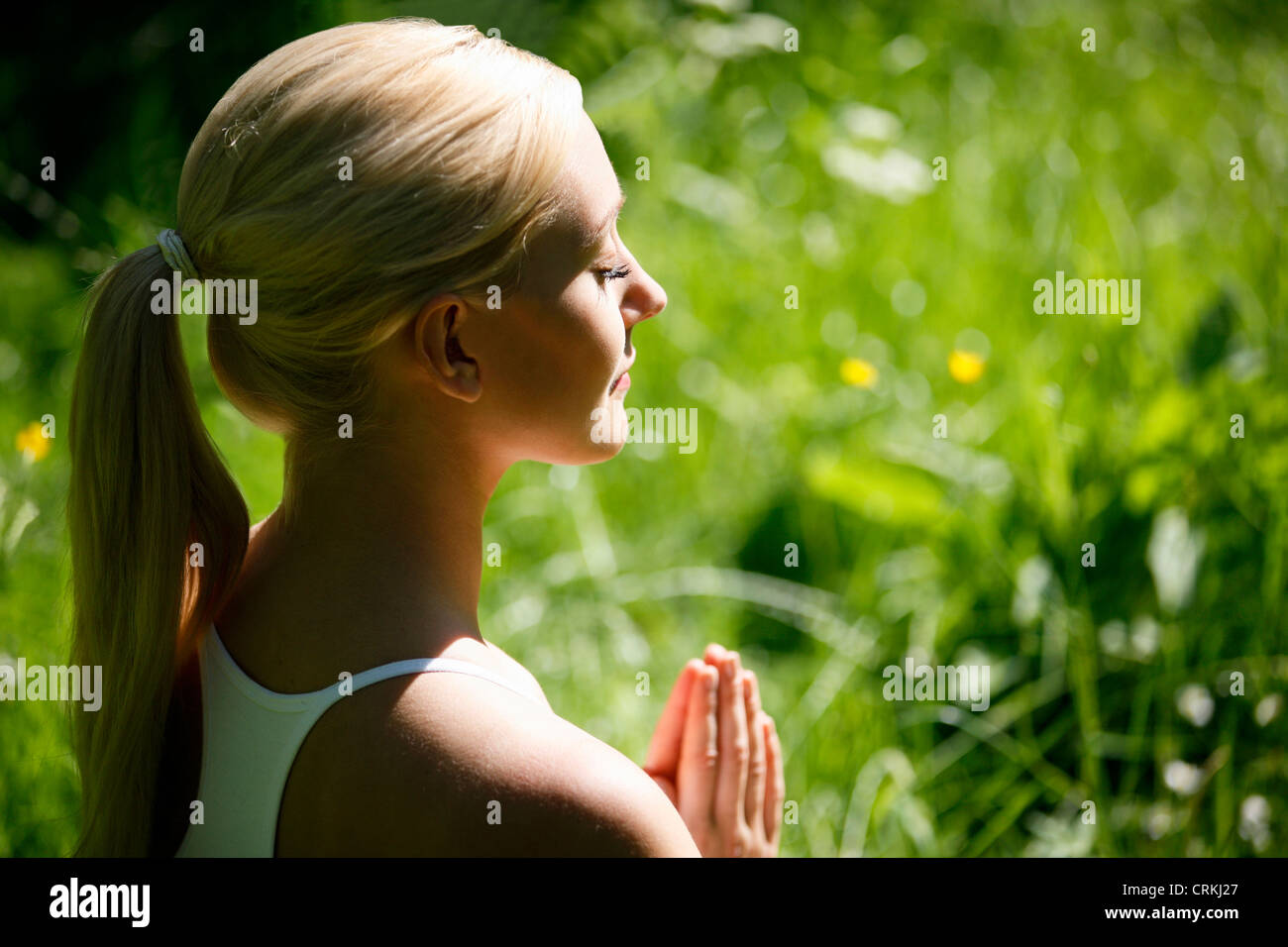 A young woman practicing yoga outside, hands in prayer position Stock ...