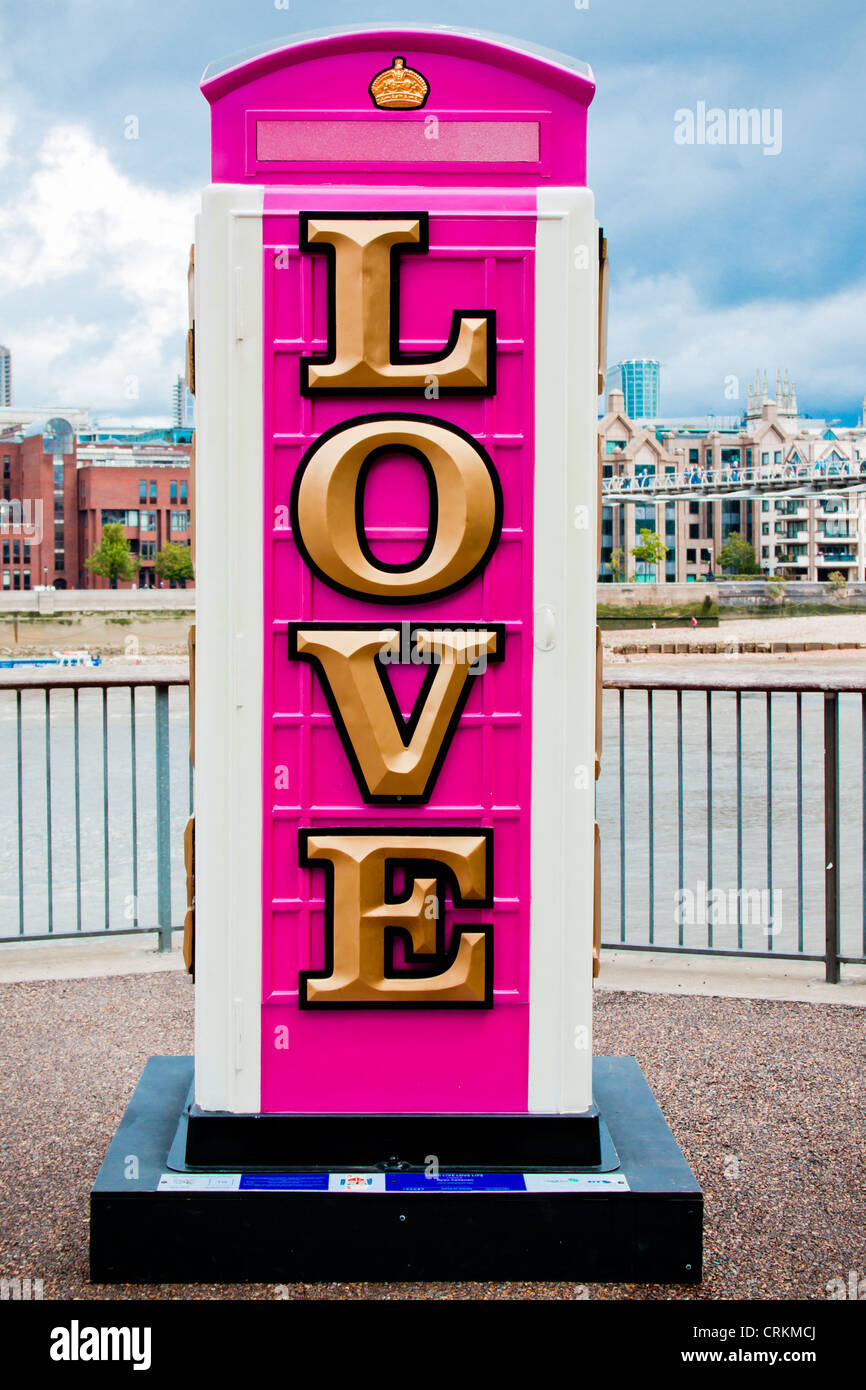 A UK telephone box painted pink with the words LOVE in gold emblazoned ...