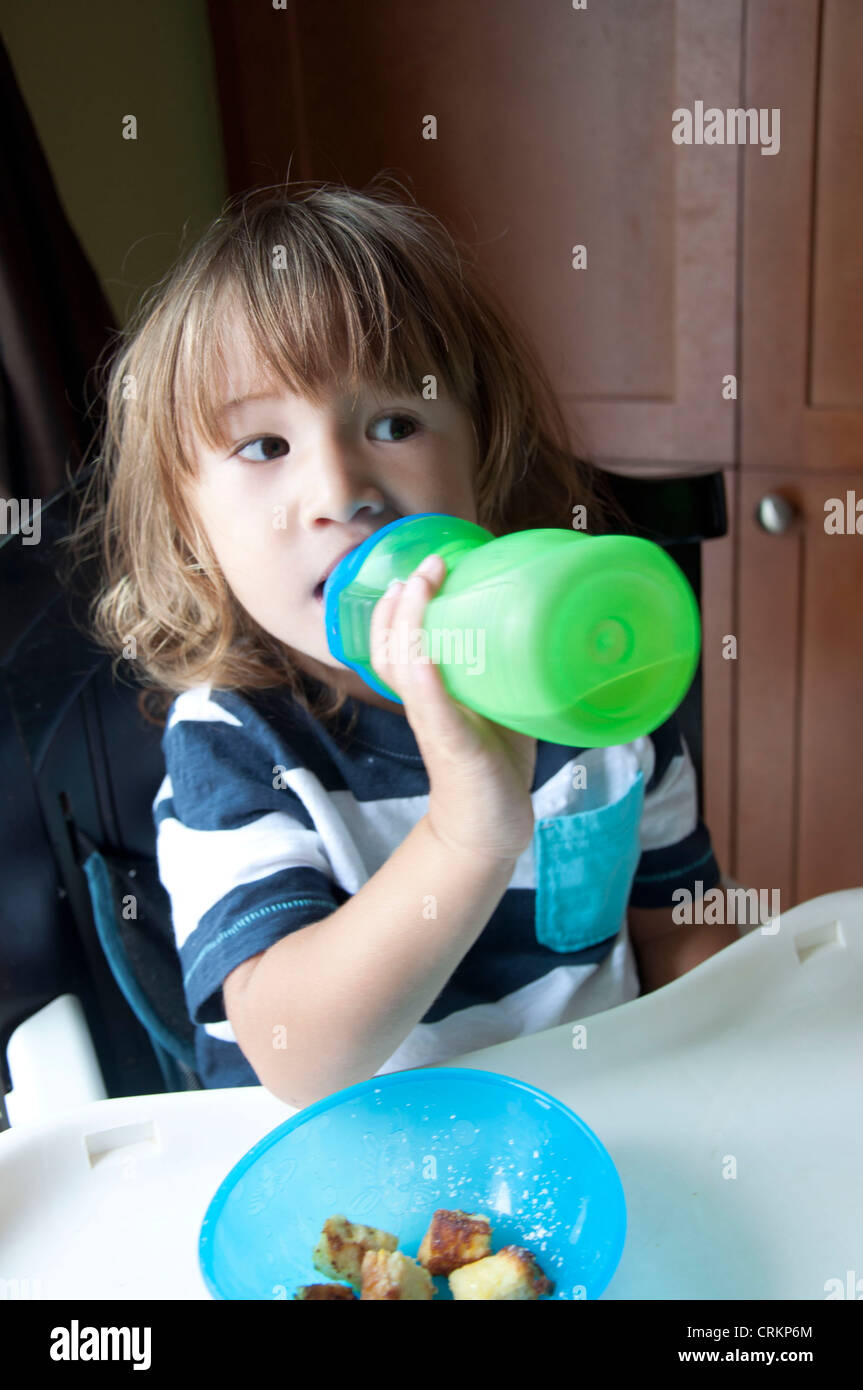 Cute baby boy kid drinking in high chair Stock Photo - Alamy