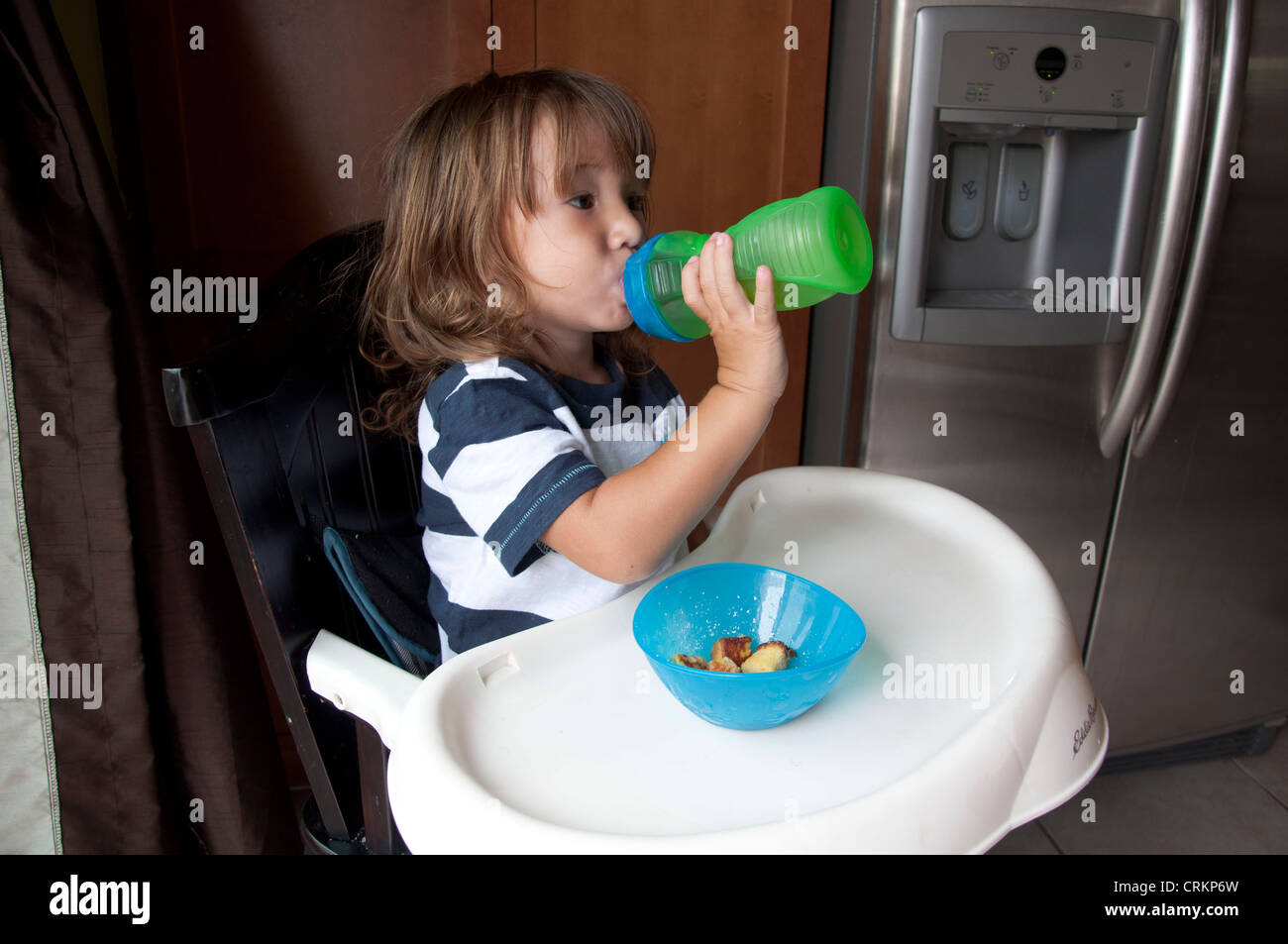 Cute baby boy kid drinking in high chair Stock Photo - Alamy