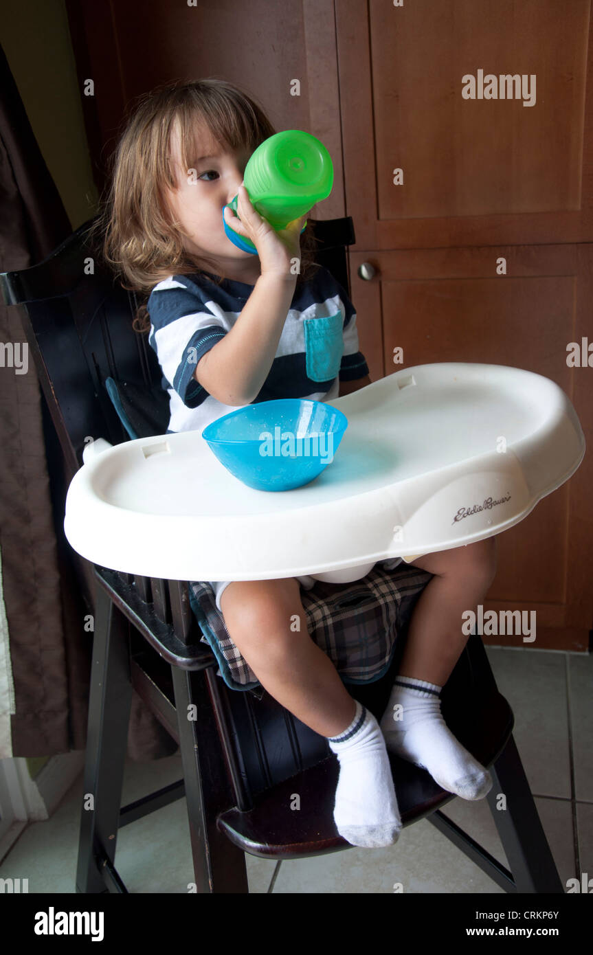 Cute baby boy kid drinking in high chair Stock Photo - Alamy