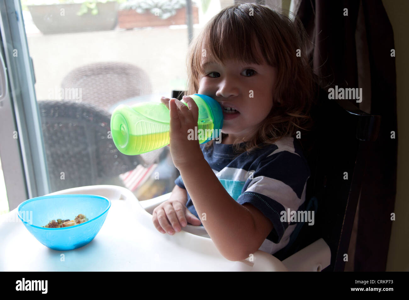 Cute baby boy kid drinking in high chair Stock Photo - Alamy