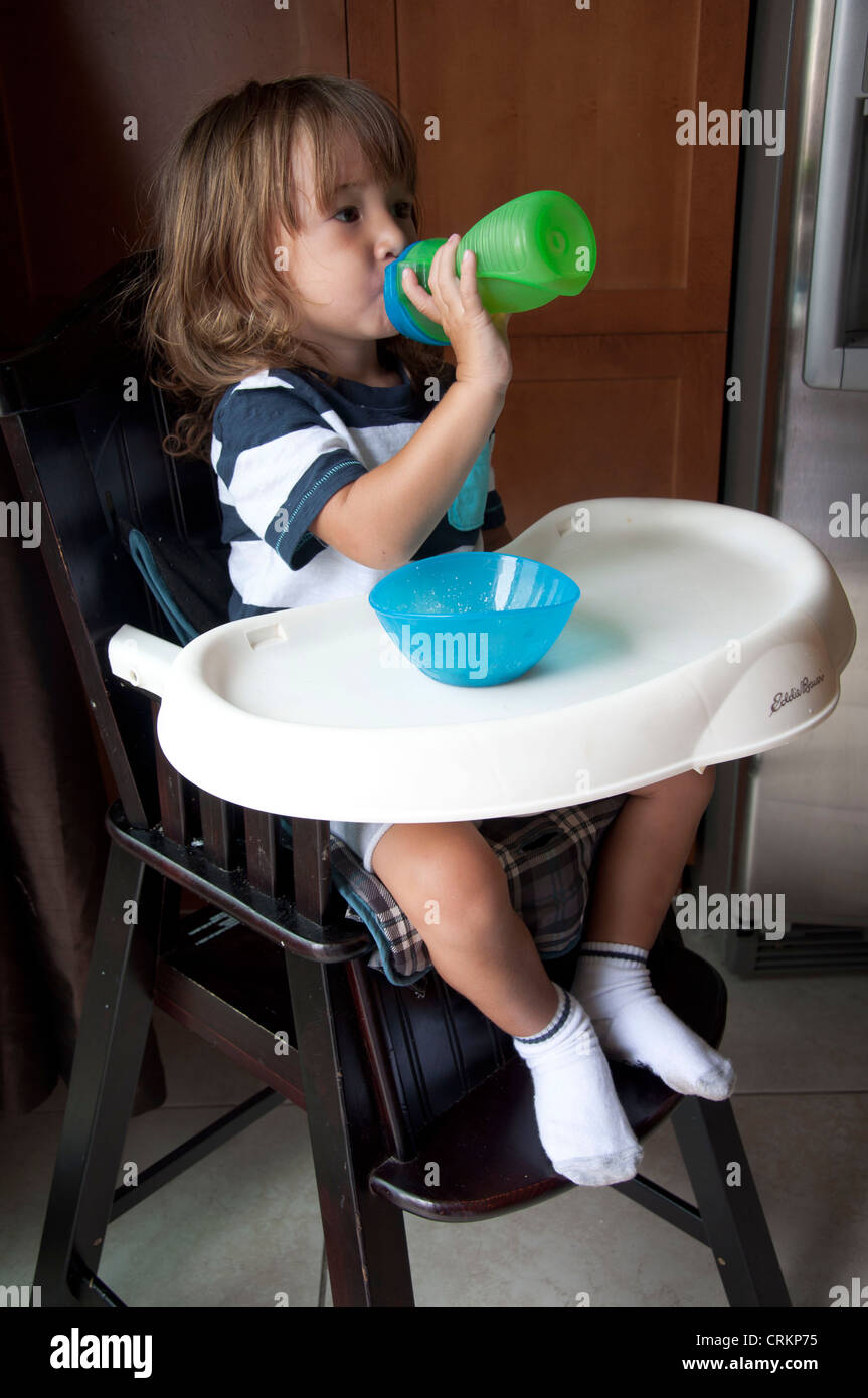 Cute baby boy kid drinking in high chair Stock Photo - Alamy