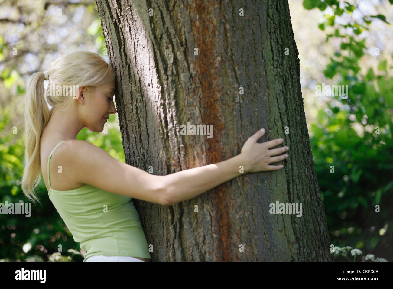 A young woman hugging a tree, head resting against its trunk Stock ...