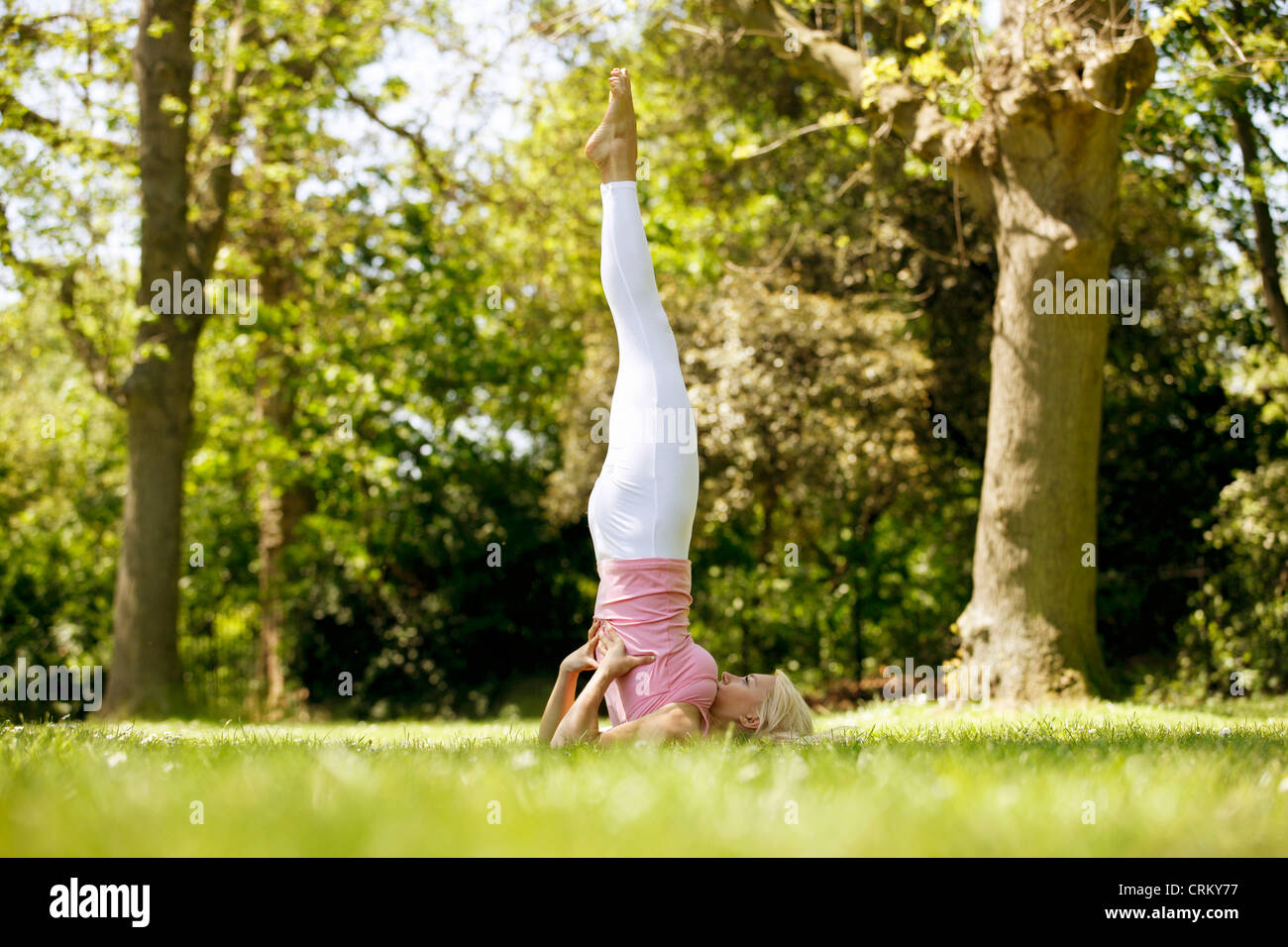 A young woman doing a shoulder stand outside Stock Photo - Alamy