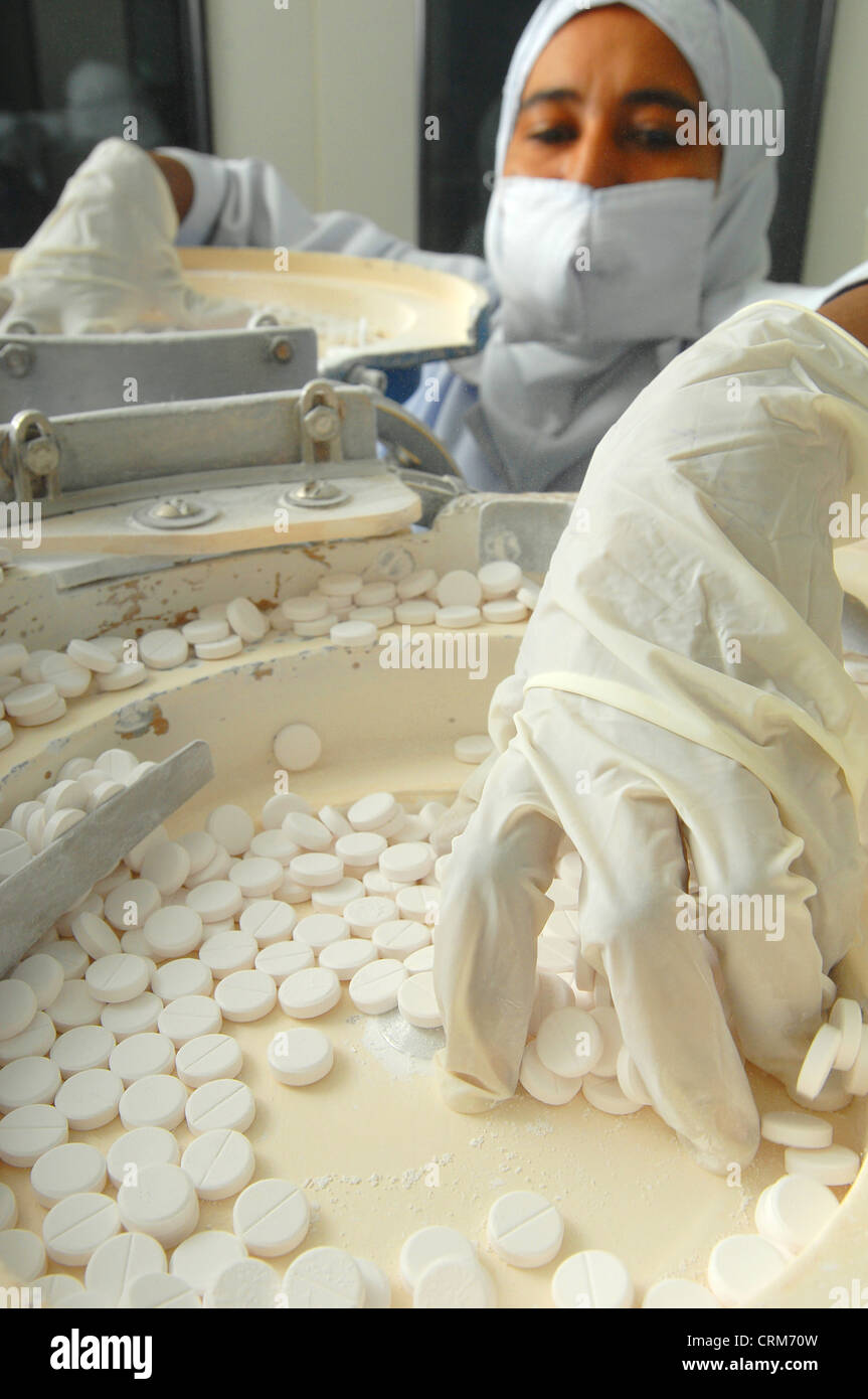 A pharmaceutical technician selects tablets from a container on the ...