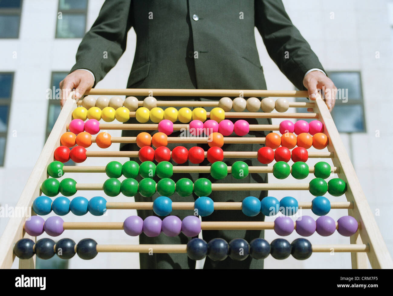 Man in suit standing behind an abacus Stock Photo - Alamy