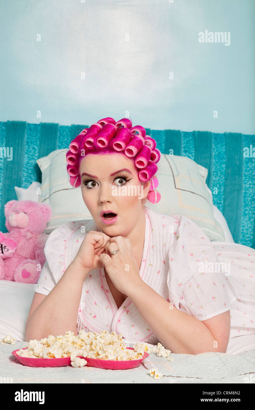 Shocked young woman with popcorn lying on bed while looking away Stock ...