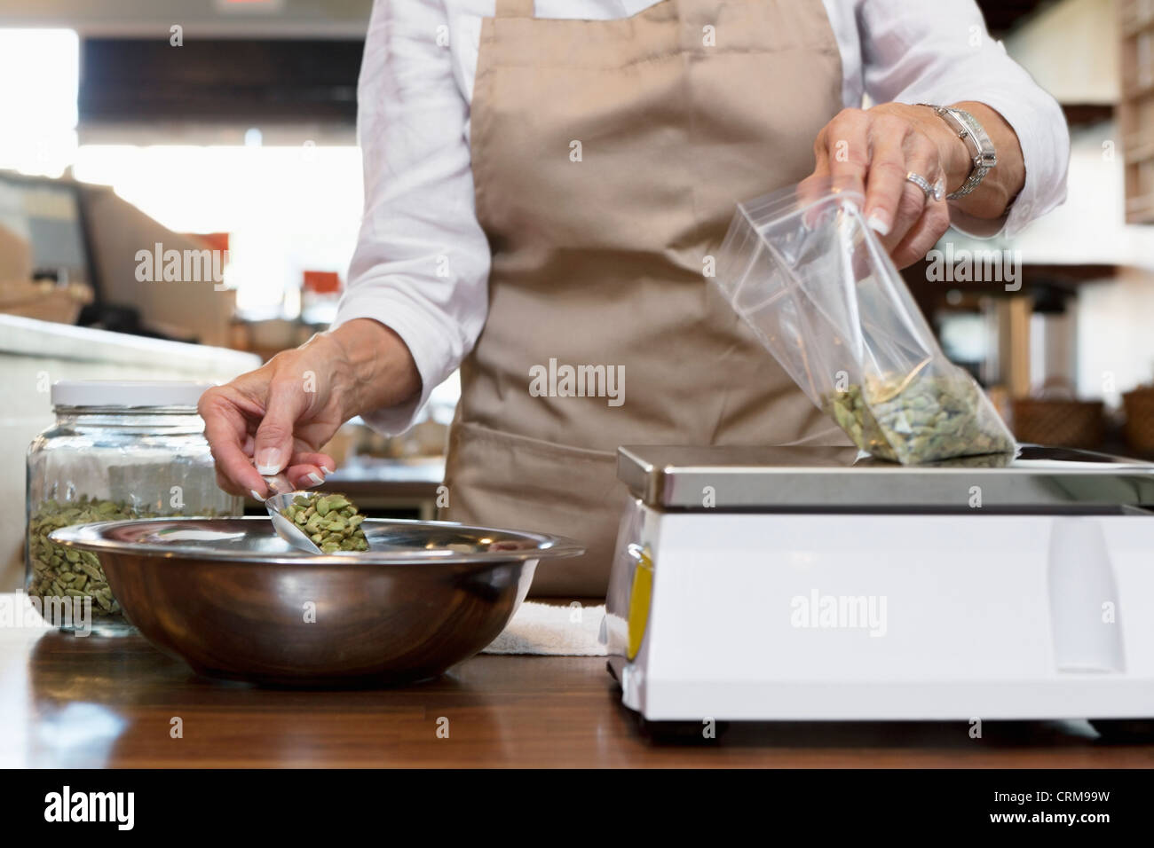Midsection of an employee measuring ingredient on weight scale in spice ...