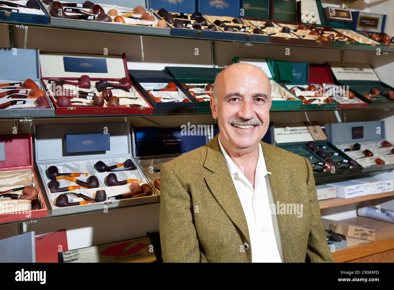Portrait of tobacco shop owner with pipes in background Stock Photo - Alamy