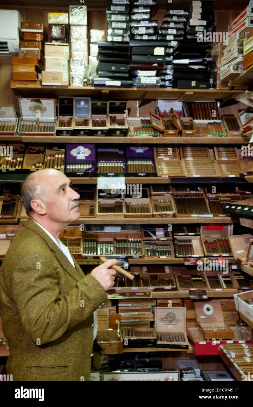 Mature tobacco shop owner looking at cigars on display Stock Photo - Alamy