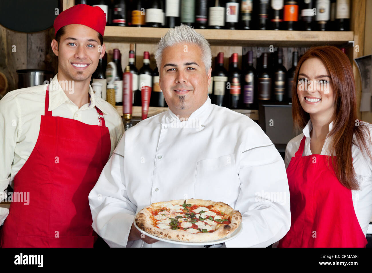 Portrait of a happy chef holding pizza with wait staff Stock Photo - Alamy