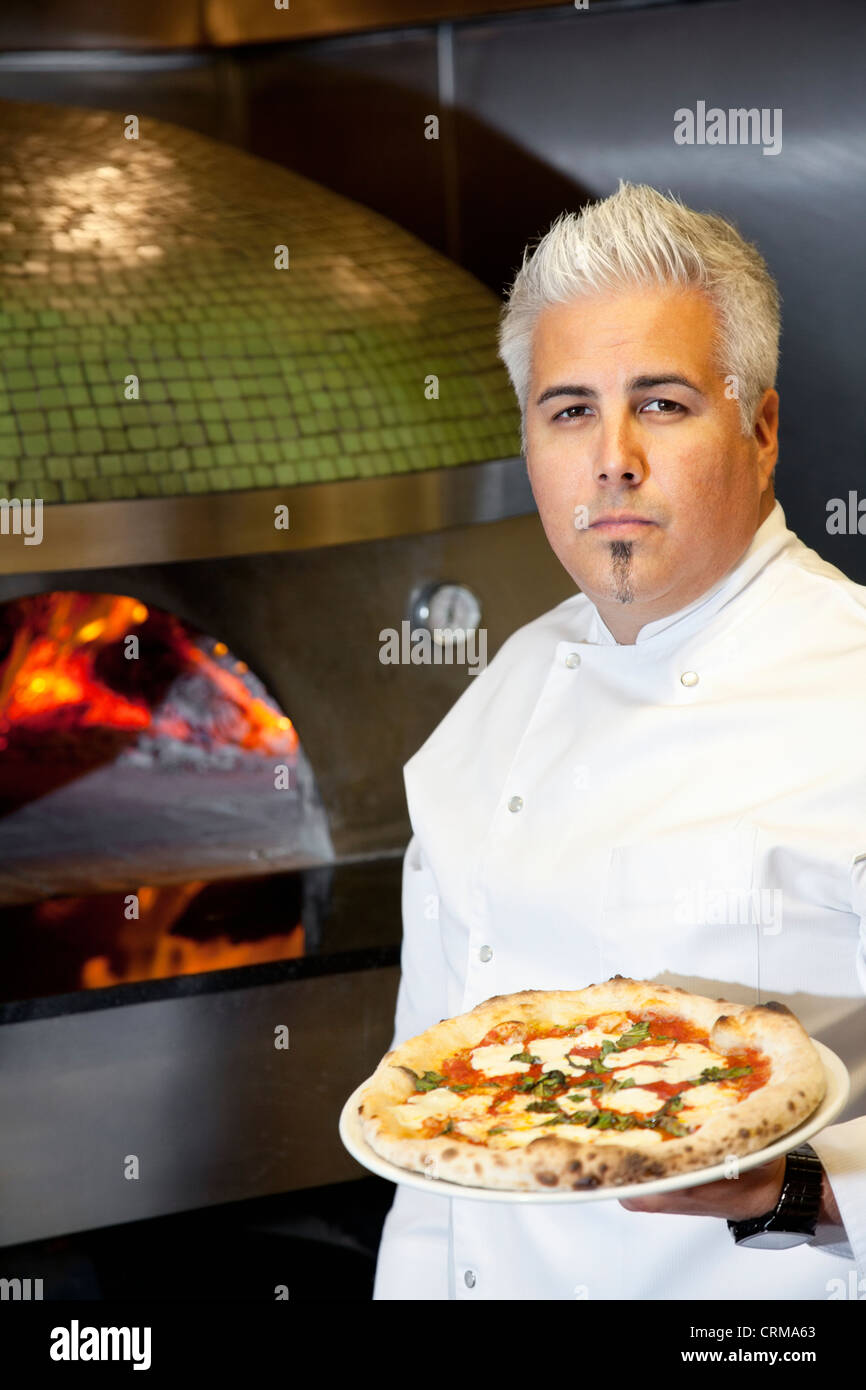Portrait of a confident mid adult chef holding pizza Stock Photo - Alamy