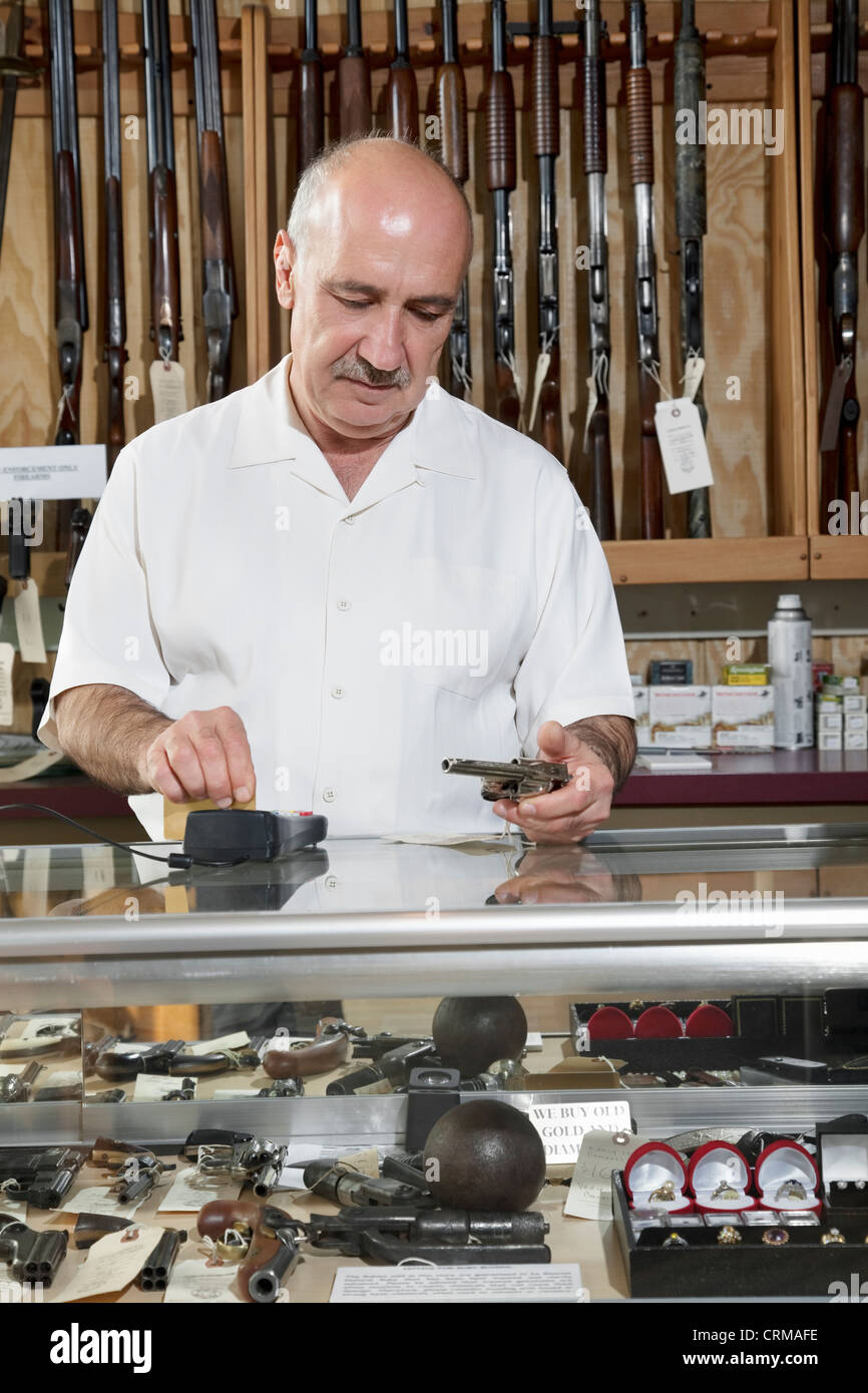 Mature male merchant at gun shop with credit card reader Stock Photo ...