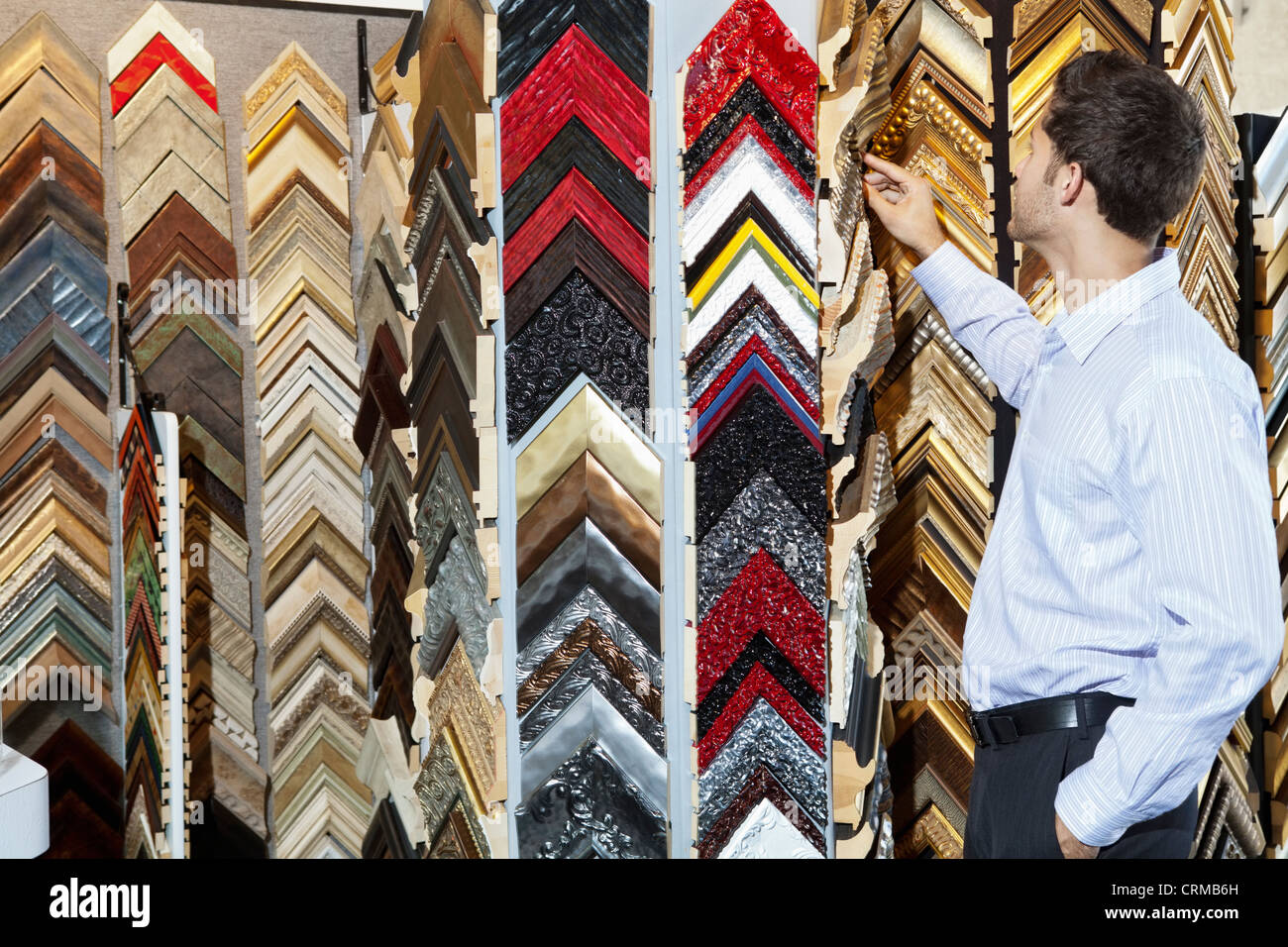 Young man looking at multi colored frames in store Stock Photo - Alamy