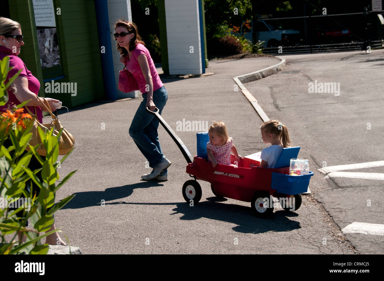Mother pulling children in red wagon Stock Photo - Alamy