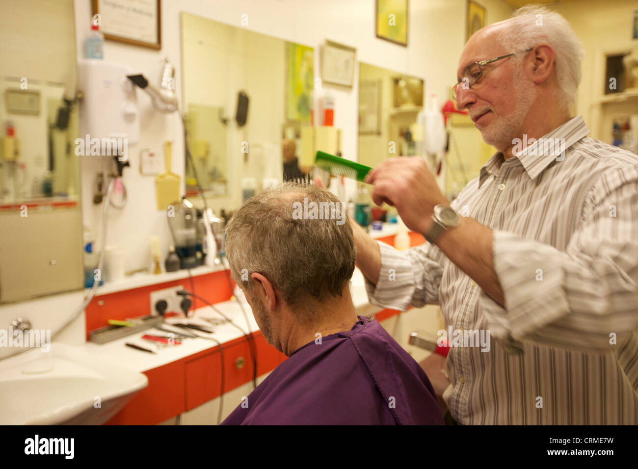Barber cutting senior man's hair in barbershop Stock Photo - Alamy