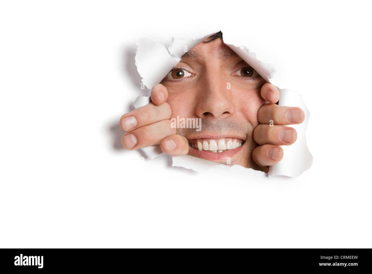 Portrait of a happy young Hispanic man peeking from ripped paper hole ...
