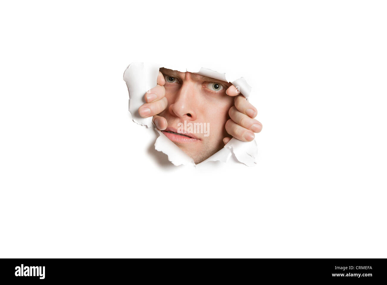Portrait of a mid adult Caucasian man peeking from ripped white paper ...