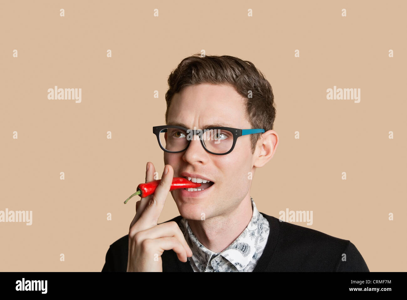 Mid adult man smoking red chili pepper over colored background Stock ...