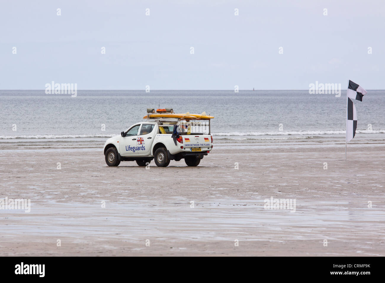 Lifeguard patrol on the beach at Westward Ho !, England next to a flag ...