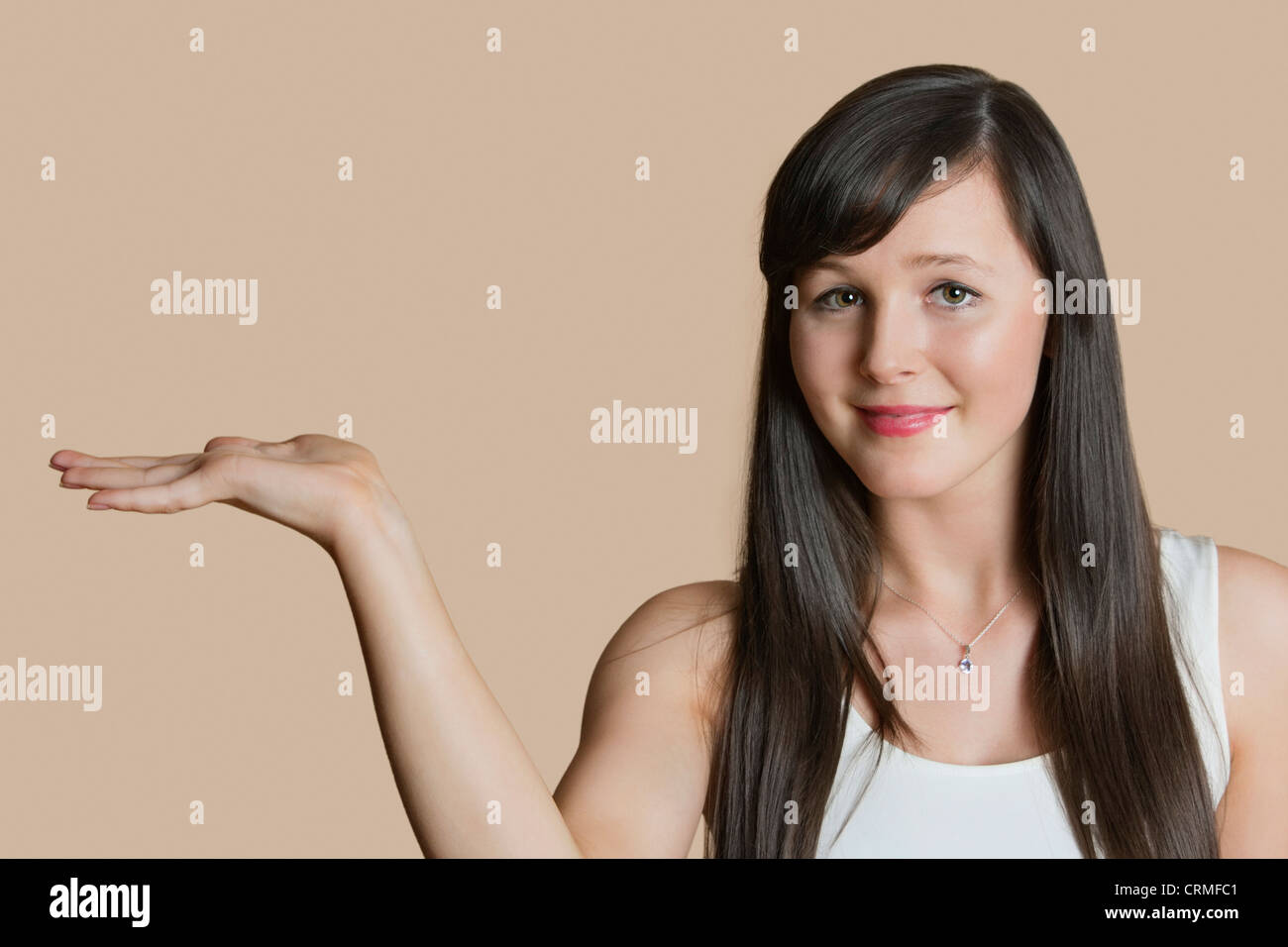Portrait of a beautiful young woman with empty hand over colored ...