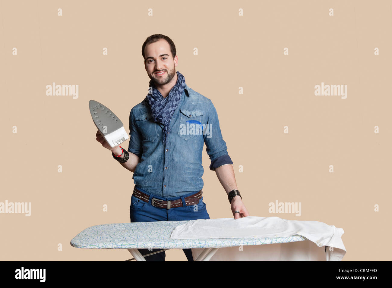 Portrait of a young man holding iron over colored background Stock ...
