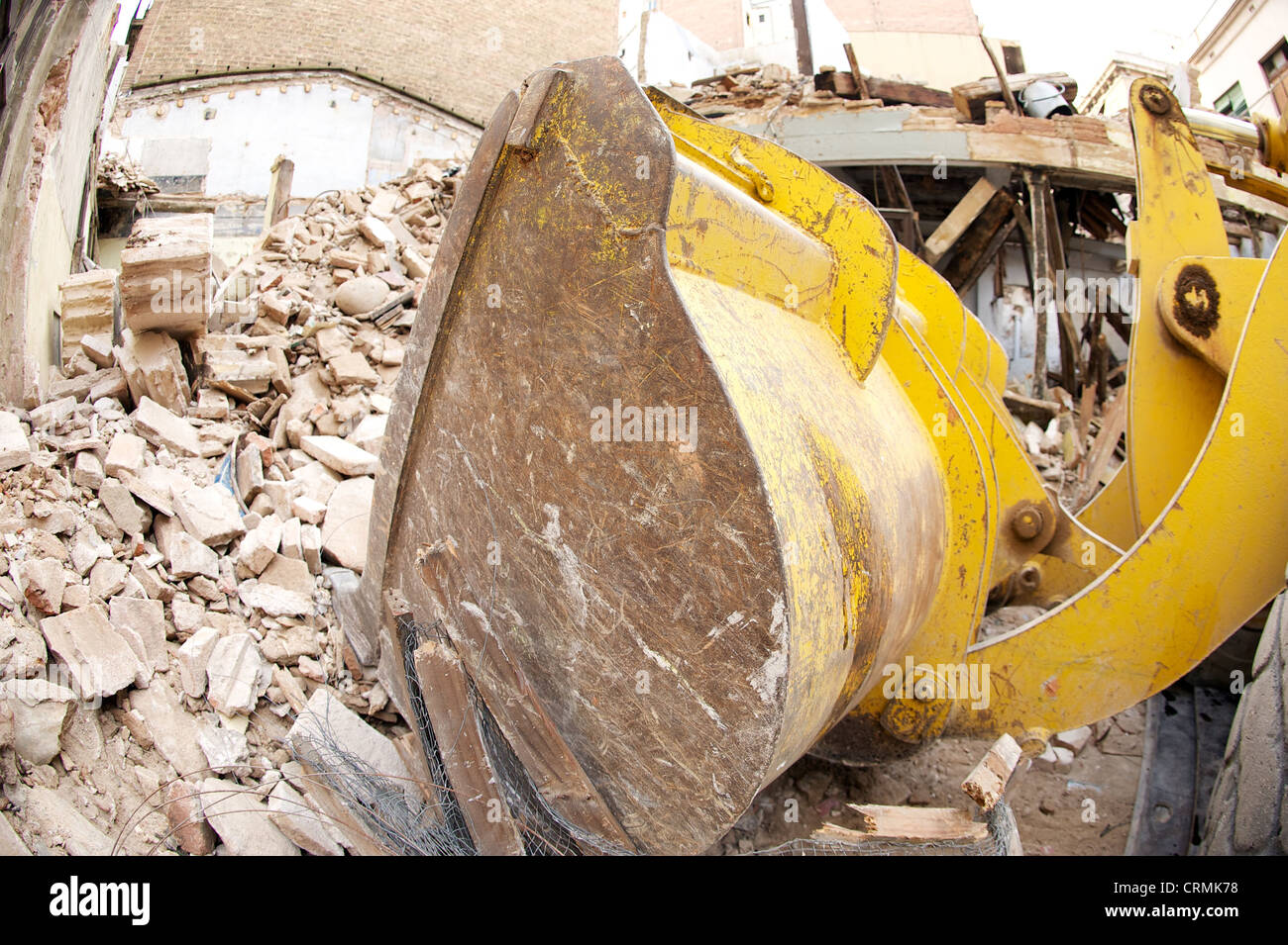 Side view of yellow digger demolishing a building and clearing the ...