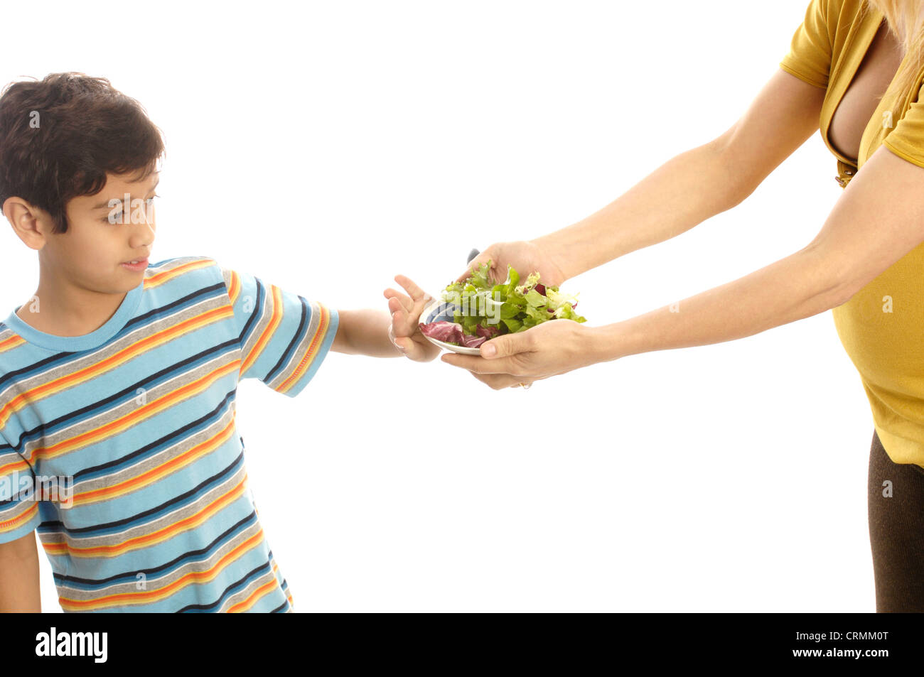 A young boy refusing to eat a bowl of salad, given to him by his mother ...