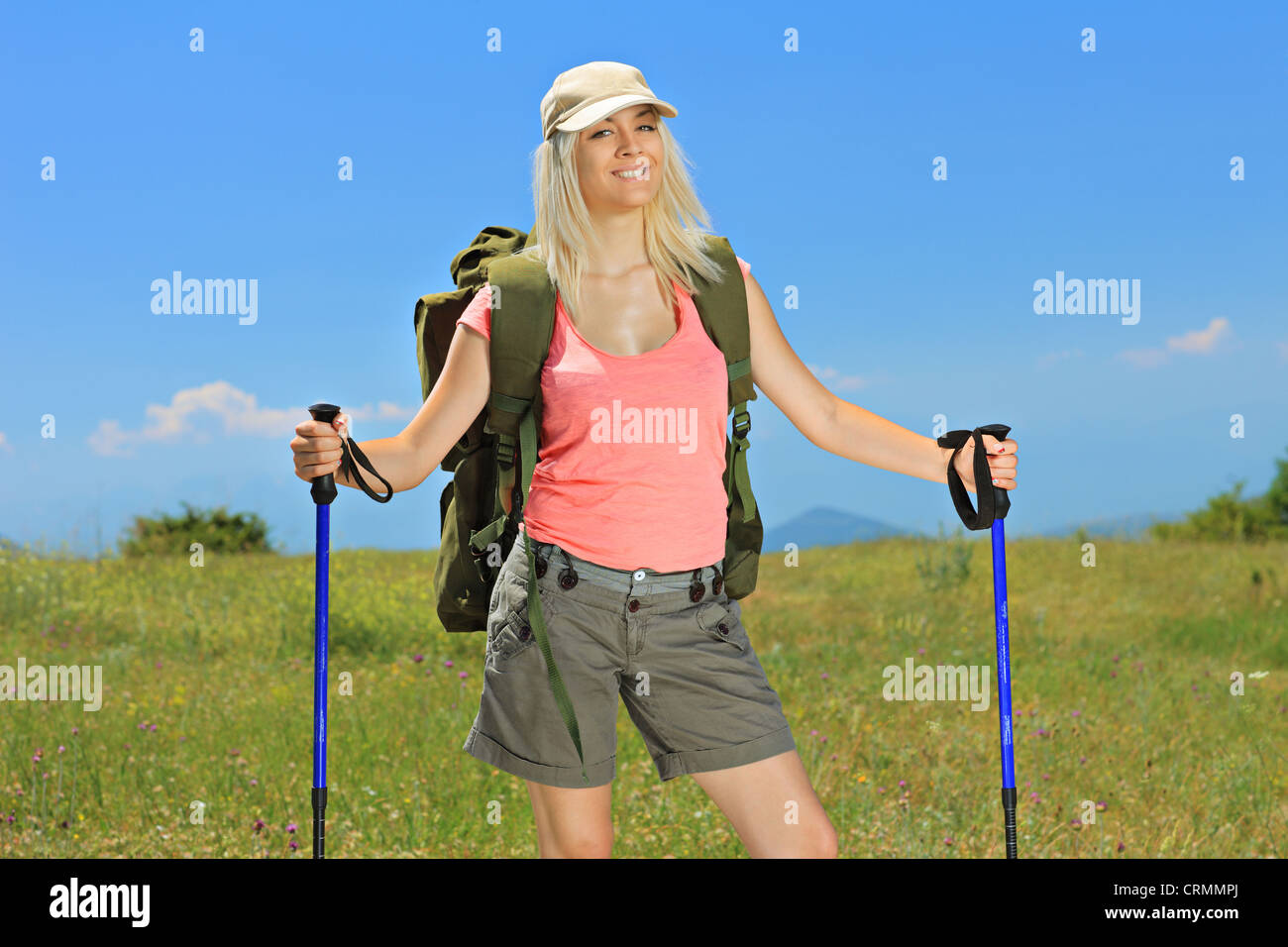 A smiling woman posing with backpack and hiking poles posing outdoor ...