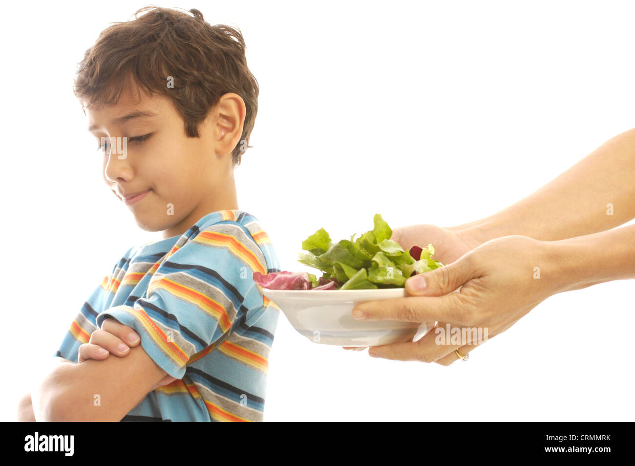 A young boy refusing to eat a bowl of salad, given to him by his mother ...