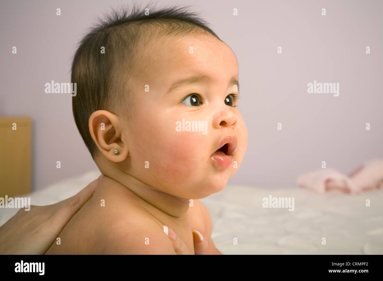 Hands massage the lower back of a six month old baby Stock Photo - Alamy