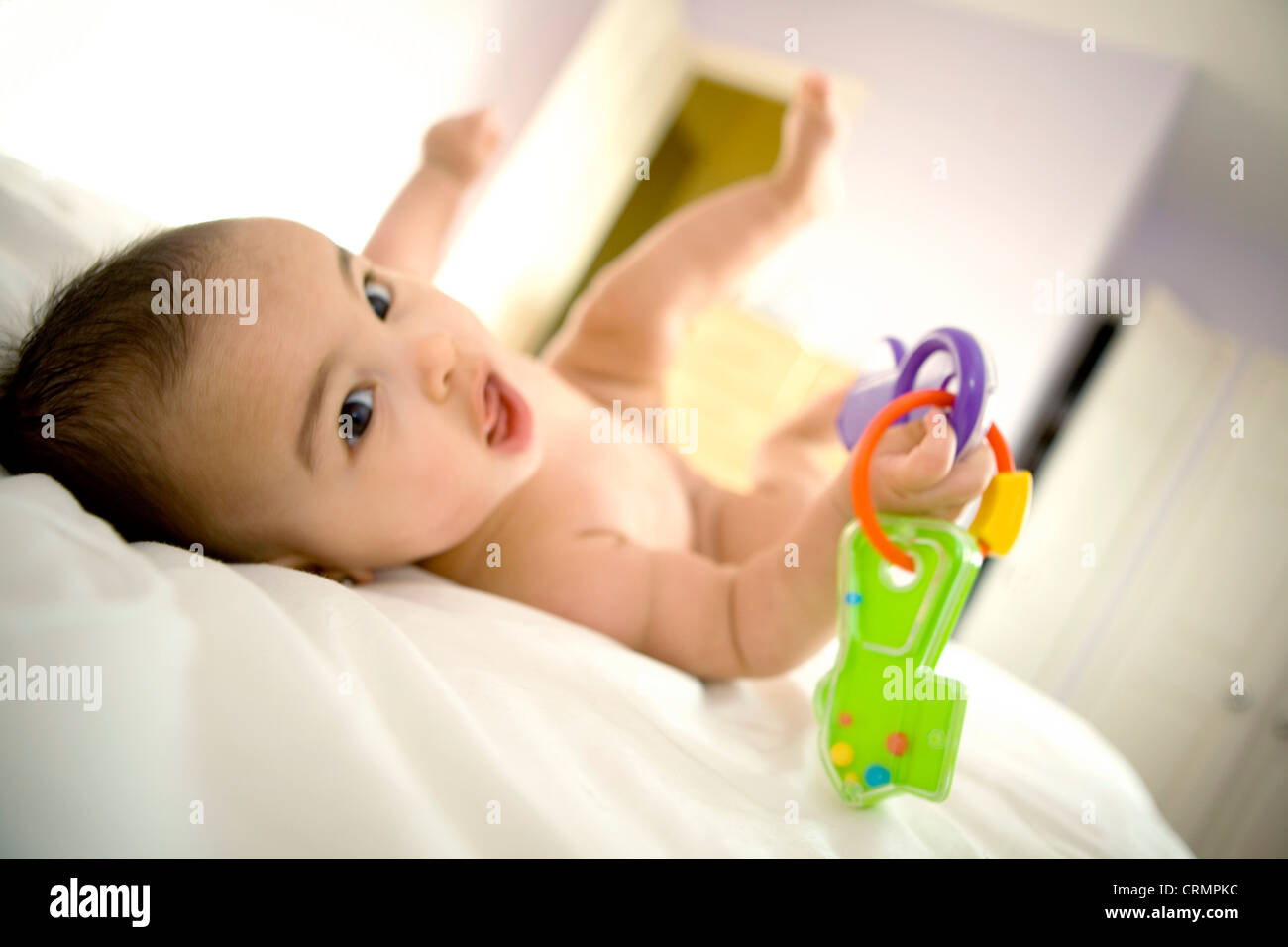 A baby laying on her back and playing with her toys Stock Photo - Alamy
