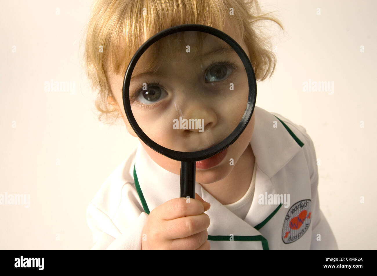 Young boy dressed as a doctor looking through a magnifying glass Stock ...
