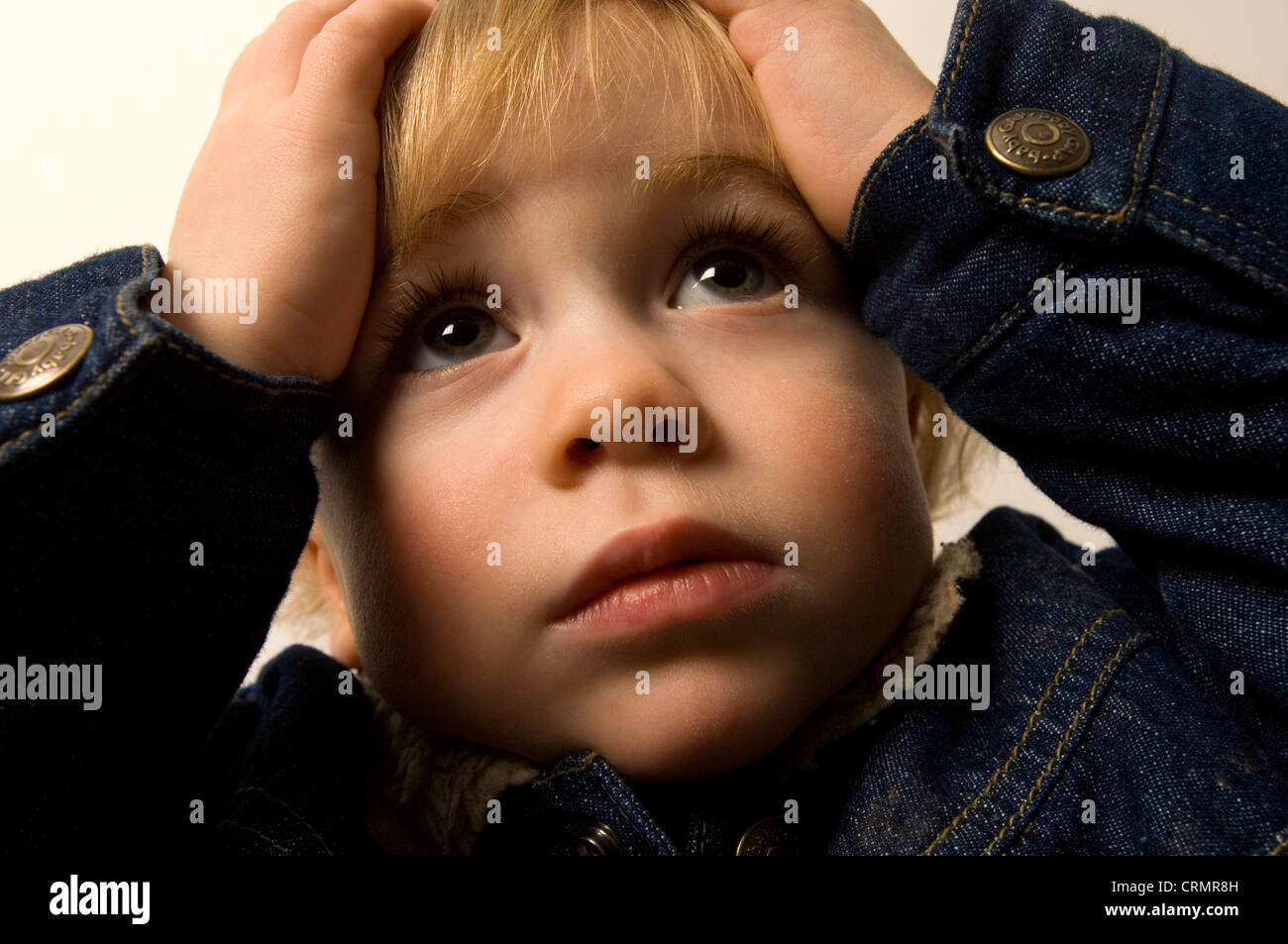 Young boy holding his head with his hands Stock Photo - Alamy