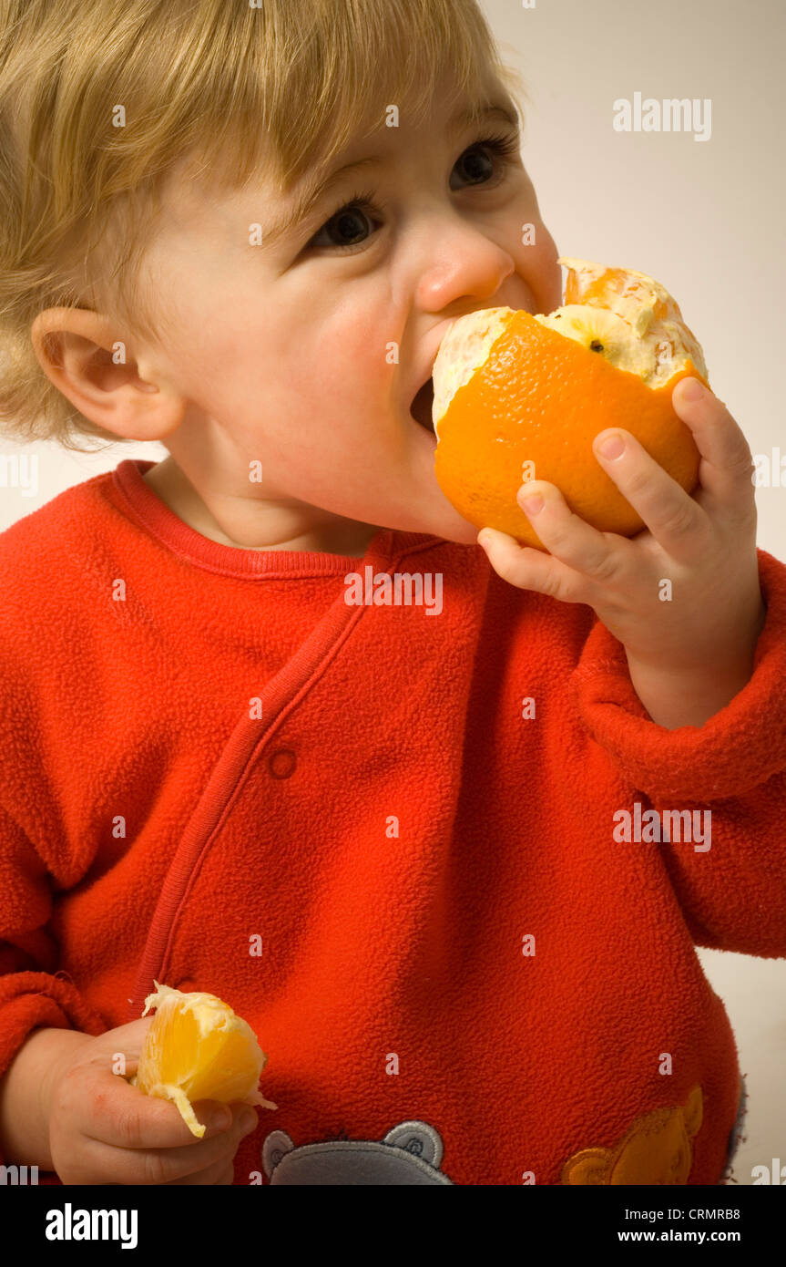 Young boy eating an orange Stock Photo - Alamy