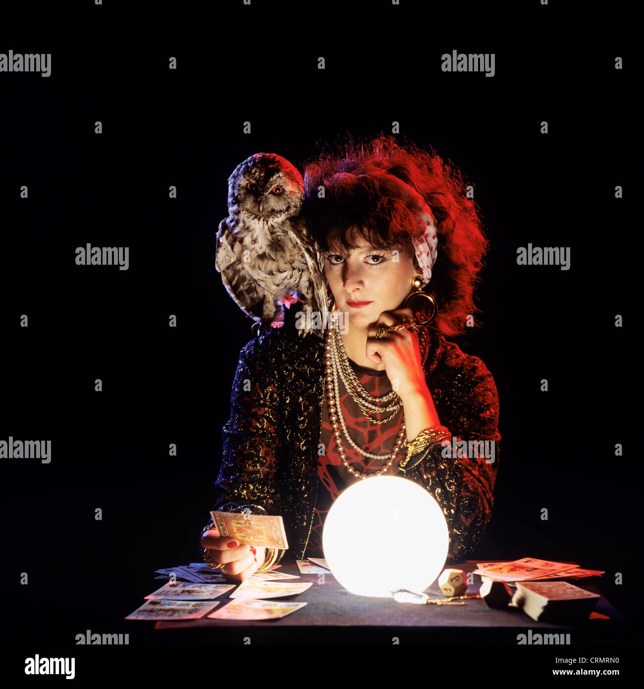 Gipsy fortune teller with an owl on her shoulder, tarot cards and lit ...