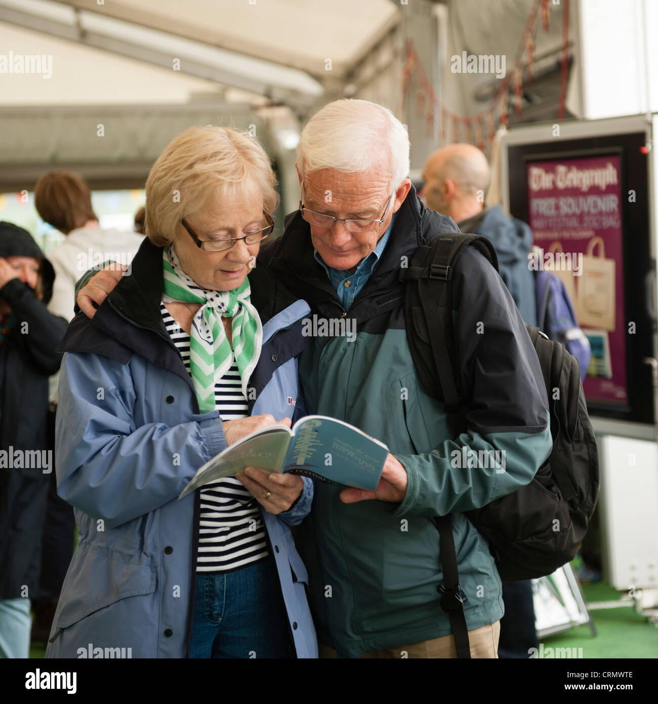 Visitors reading the programme at The Telegraph Hay Festival, June 2012 ...