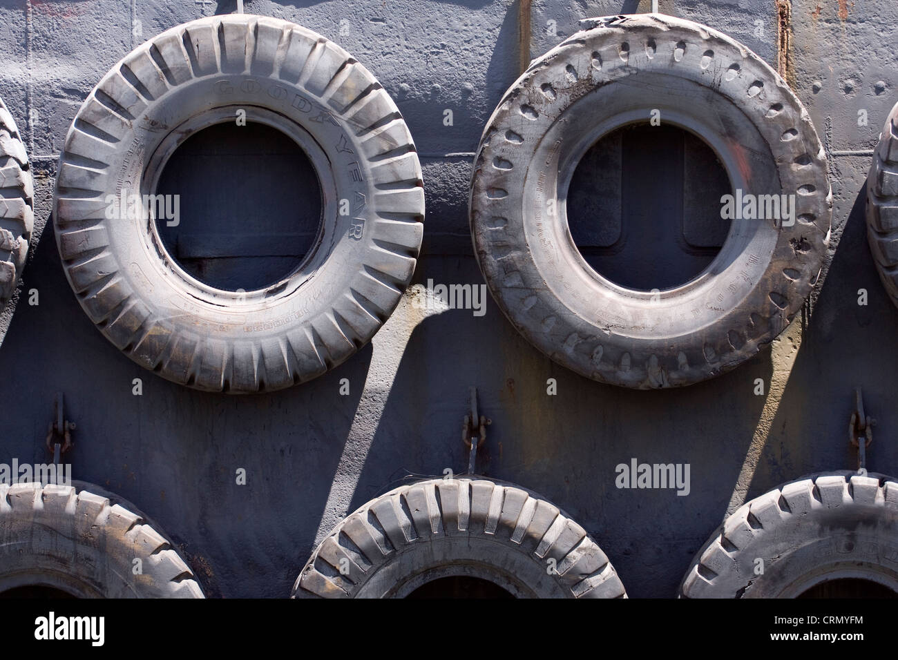 Old tires used as protective bumpers suspended on the outside hull of a ...