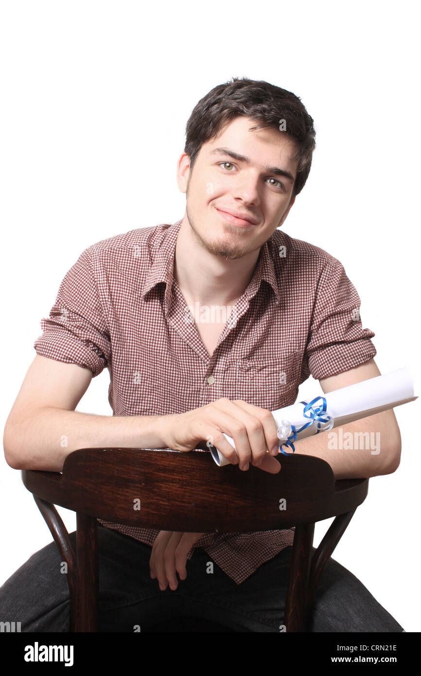 High school male graduate holding his graduating diploma sitting on a ...